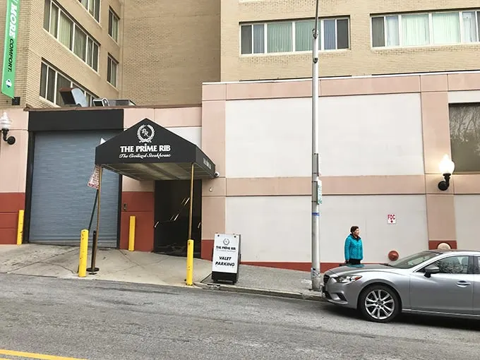 The understated elegance of The Prime Rib's entrance promises what lies beyond—a Baltimore dining institution where time stands deliciously still.