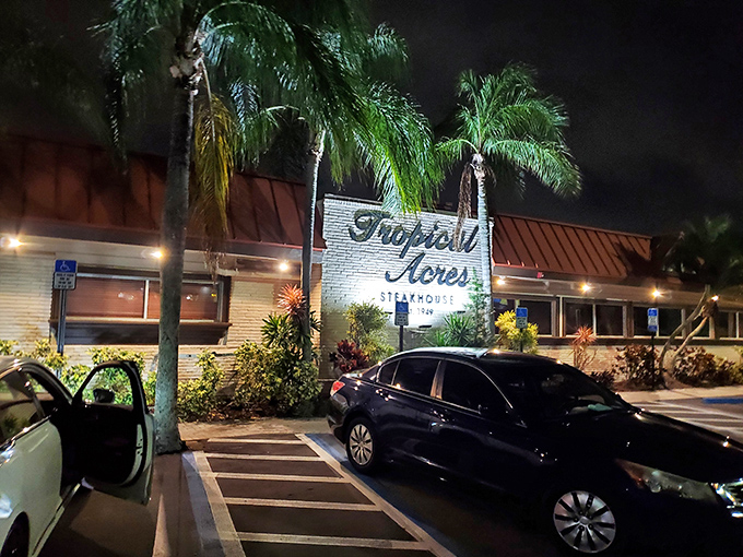 The unassuming exterior of Tropical Acres Steakhouse, where palm trees stand guard over Florida's best-kept carnivorous secret since 1949. 