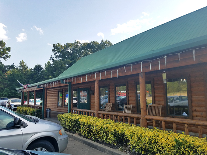 The rustic log cabin exterior of The Oaks isn't trying to impress you—until you taste what's cooking inside. Green roof, wooden benches, and promises of carnivorous delight await.