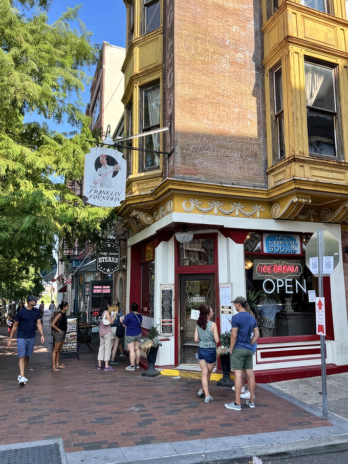 The storefront beckons like a time portal to ice cream's golden age—ornate yellow cornice, classic signage, and that brick facade promising sweet nostalgia inside.