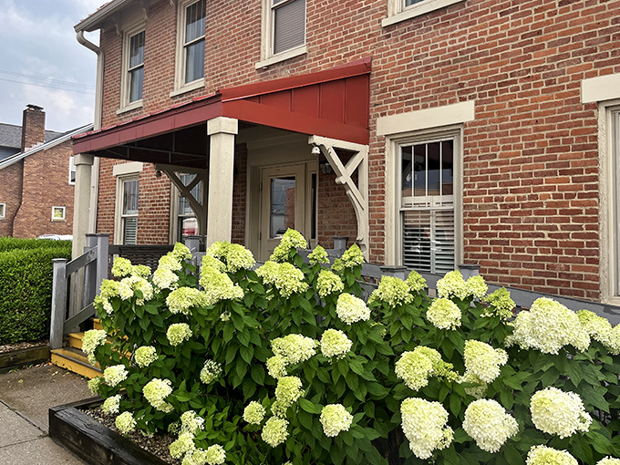 The historic brick exterior of Old Canal Smoke House welcomes you with its charming red awning and flower boxes—like a barbecue beacon calling you home.