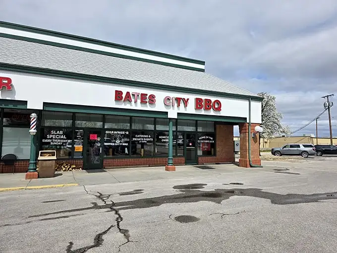 The unassuming storefront of Bates City BBQ, where stacked firewood isn't decor—it's a promise of smoky delights waiting inside.