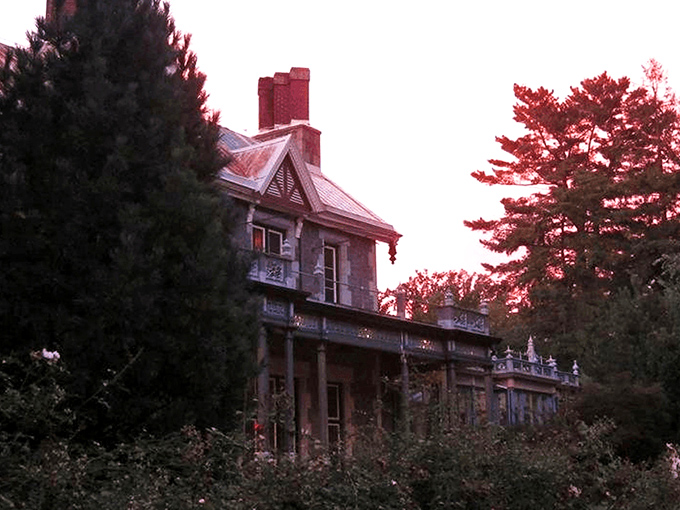 The mansion glows amber against the twilight sky, its stone façade and pointed gables silently whispering tales from another century. Like a Victorian ghost story come to life.