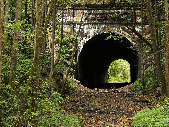 Nature reclaims what man abandoned at Moonville Tunnel, where vibrant greenery frames this portal to the past. The perfect backdrop for both daytime adventures and nighttime frights.