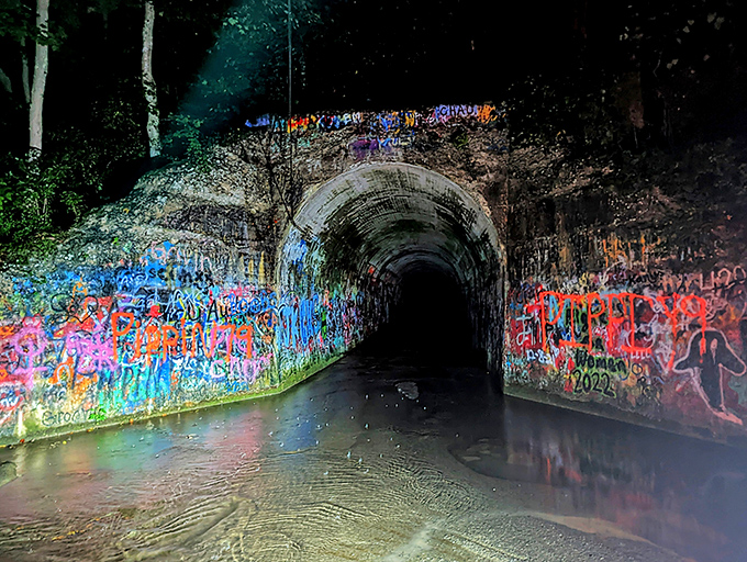 The entrance beckons with an eerie invitation – colorful graffiti leading into darkness where legends and water converge in Tennessee's most notorious tunnel.