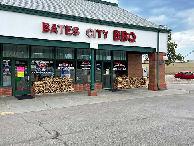 The unassuming storefront of Bates City BBQ, where stacked firewood isn't decor—it's a promise of smoky delights waiting inside.