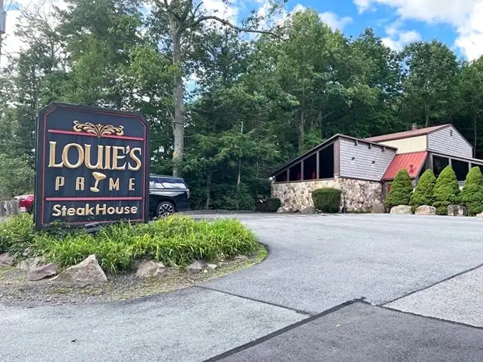 The forest parts to reveal culinary treasure – Louie's Prime Steak House stands proudly among the trees, its stone foundation and wooden charm beckoning hungry travelers.