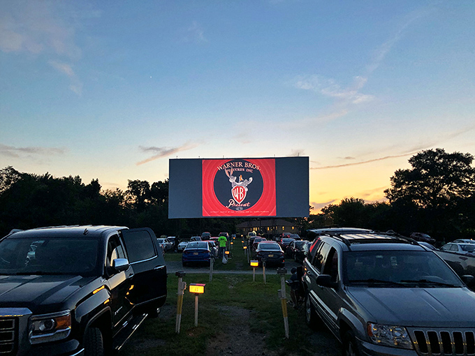 Twilight magic unfolds as families gather beneath Bengies' massive screen, where the "Good Evening Folks" welcome glows against a Maryland sunset.