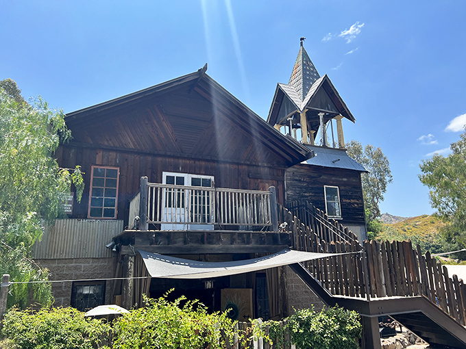 The Old Place stands proudly against the California sky, its weathered wooden exterior and bell tower looking like they've been waiting for John Wayne to ride up.