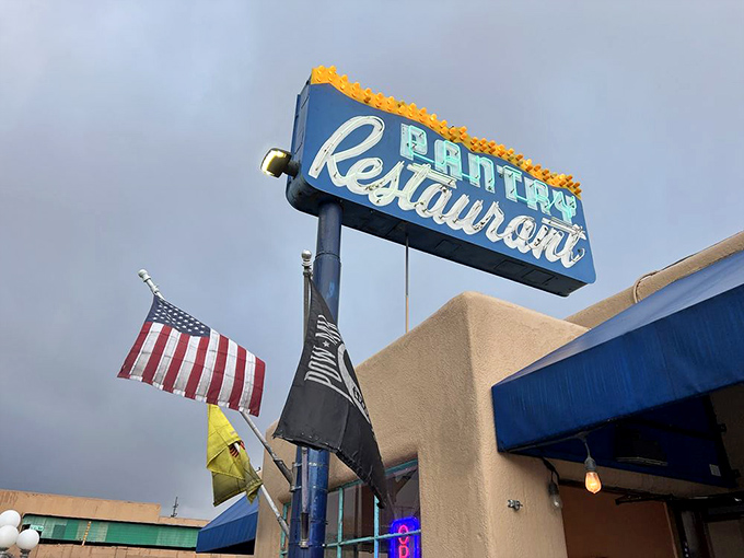The iconic blue Pantry sign stands like a beacon of breakfast hope against the New Mexico sky, promising culinary salvation to hungry souls below.