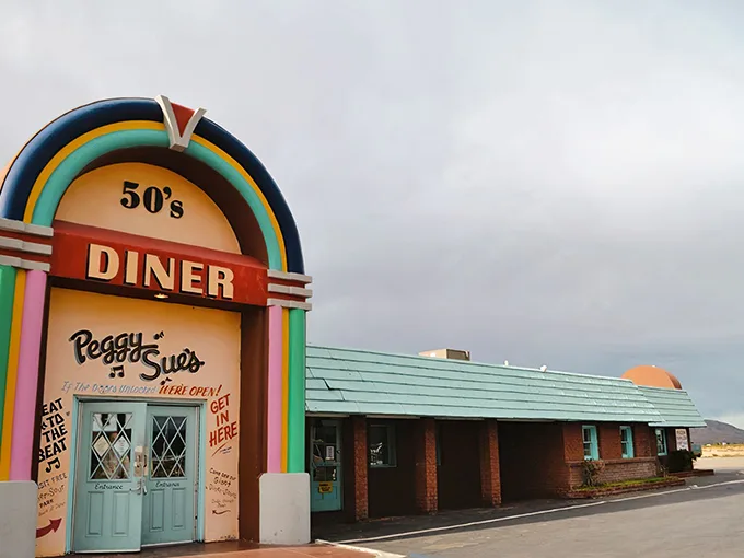 The rainbow-colored archway of Peggy Sue's beckons like a time portal in the desert. This isn't just a pit stop—it's a destination.