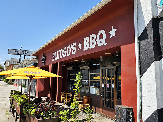 The crimson facade of Bludso's stands like a temple to Texas tradition, complete with succulent planters that say, "Slow down, you're about to enter sacred smoke territory."