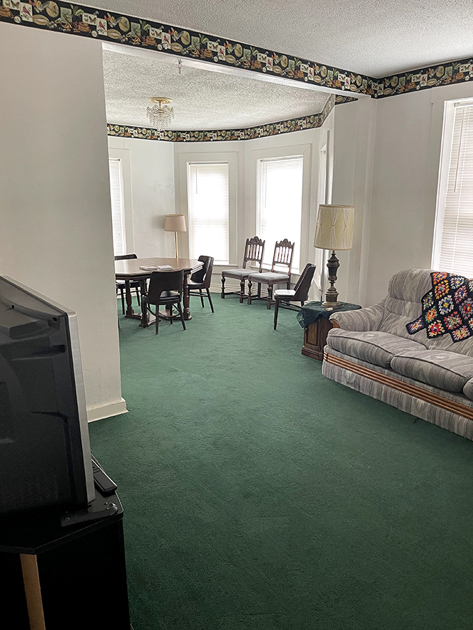 The living room's bay windows and vintage furniture offer a comfortable space for ghost hunting—or becoming part of the haunted history yourself.