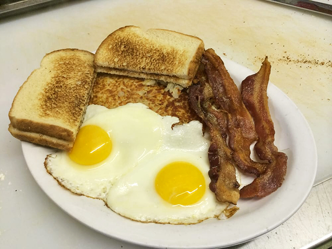 The breakfast trifecta—sunny-side-up eggs, perfectly crisped bacon, and toast—simple perfection that never goes out of style.
