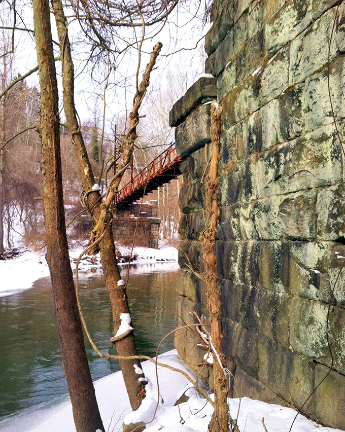 Winter transforms the park into a monochromatic wonderland, with the stone bridge standing in stark contrast against the snow-dusted landscape.