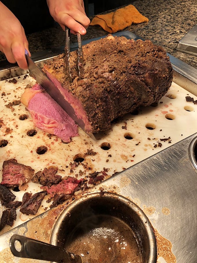 Prime rib being carved to order—the moment that makes waiting in line worthwhile. That perfect pink center is the stuff of carnivore dreams.