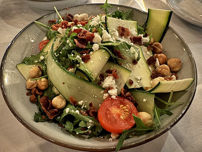 A salad that actually excites the palate—crisp cucumber, hazelnuts, and what appears to be bacon prove that vegetables can party too. This isn't rabbit food; it's sophisticated balance.