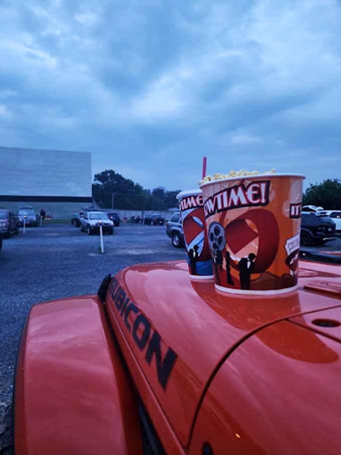 The quintessential drive-in experience captured in one image: vintage car, classic popcorn, and that blue twilight glow before the show.
