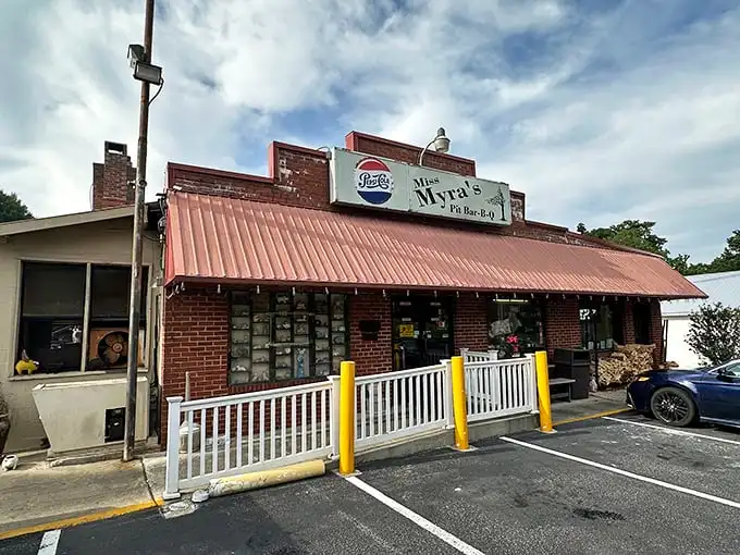 Miss Myra's exterior beckons with its humble brick facade and red awning – proof that BBQ greatness often hides in plain sight.