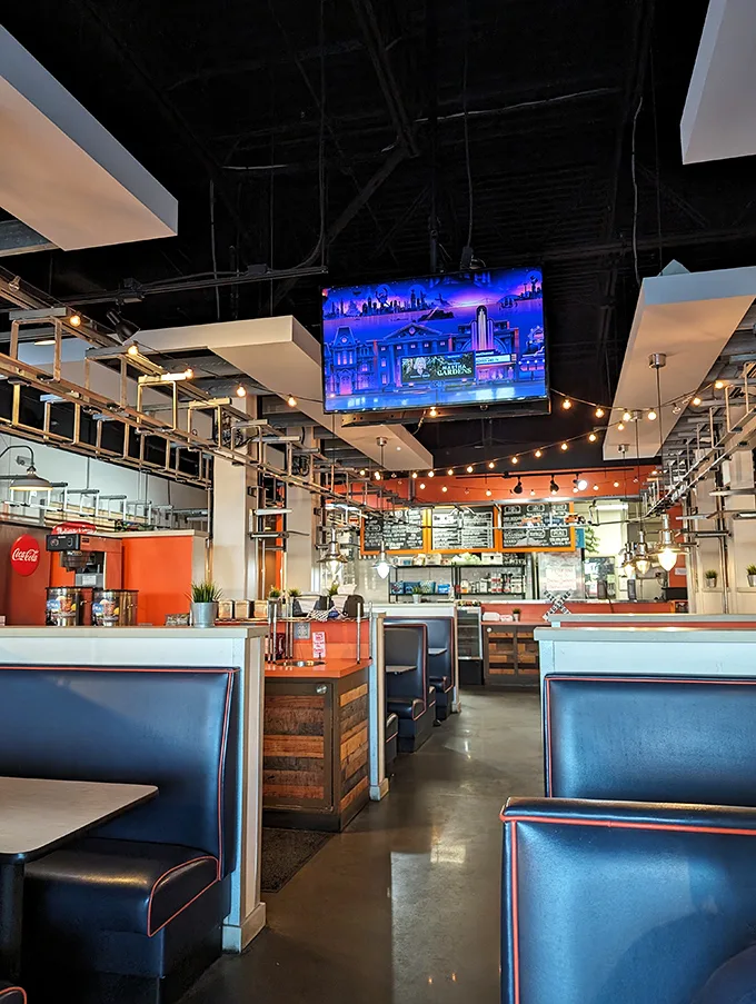 Industrial-chic meets railway nostalgia in this thoughtfully designed space. Blue booths, string lights, and exposed ceiling create an atmosphere both modern and timeless.