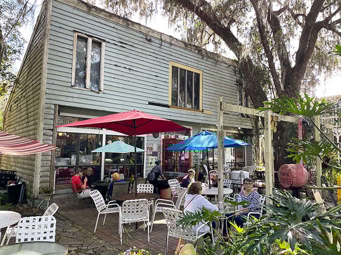 Old Florida Café's weathered clapboard exterior and shaded patio invite you to slow down. The umbrellas aren't just for shade—they're for extending your coffee time.