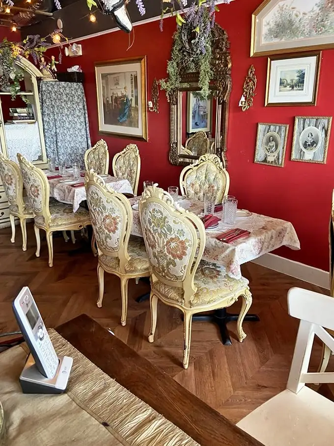 Rich crimson walls adorned with vintage frames create a space that feels like your stylish French grandmother's living room—if your grandmother had impeccable taste and a flair for the dramatic.