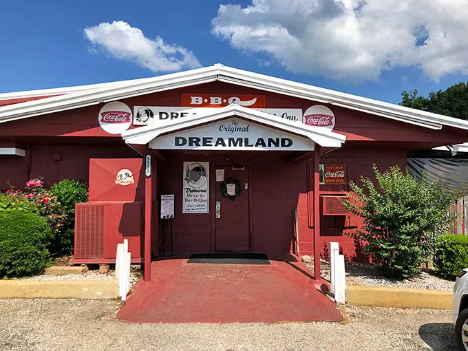 Dreamland's bright red building stands like a temple to ribs. The "BBQ" sign is just a formality – that smokestack tells the real story.