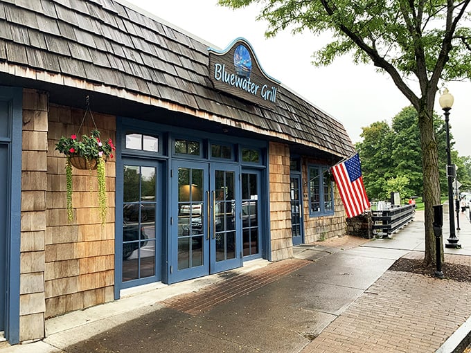 Blue Water Grill welcomes hungry travelers with cedar-shingled warmth, American flag proudly waving—like a nautical clubhouse where seafood dreams come true.