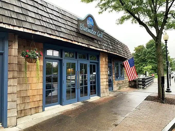Blue Water Grill welcomes hungry travelers with cedar-shingled warmth, American flag proudly waving—like a nautical clubhouse where seafood dreams come true.