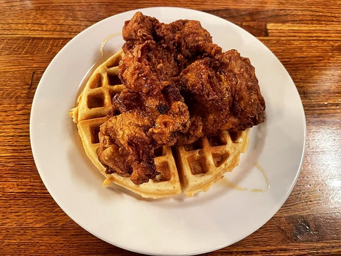 The chicken and waffle plate arrives like breakfast royalty—golden, crispy coating giving way to juicy meat, all lounging on a waffle throne.