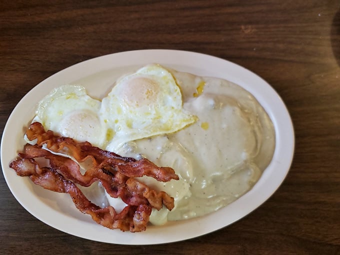 Breakfast perfection doesn't need fancy plating. Two sunny-side eggs, crispy bacon, and gravy that could make a vegetarian reconsider their life choices.