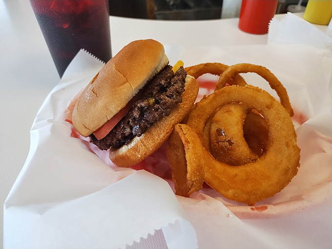 This isn't just a burger and onion rings – it's edible poetry on wax paper, where beef meets bun in a relationship that was clearly meant to be.