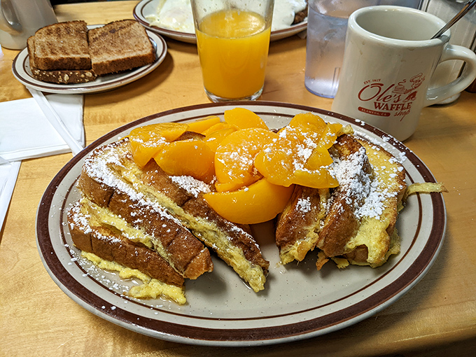 A symphony of textures: golden French toast crowned with fresh peaches and a cloud of whipped cream that makes morning meetings seem entirely optional. 