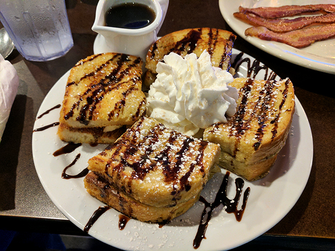French toast that looks like it graduated from culinary school with honors—golden, griddled perfection crowned with chocolate drizzle and whipped cream.