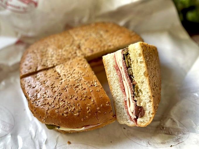 A cross-section reveals the architectural marvel that is a proper muffuletta—layer upon precise layer of meats, cheeses, and that magical olive salad.
