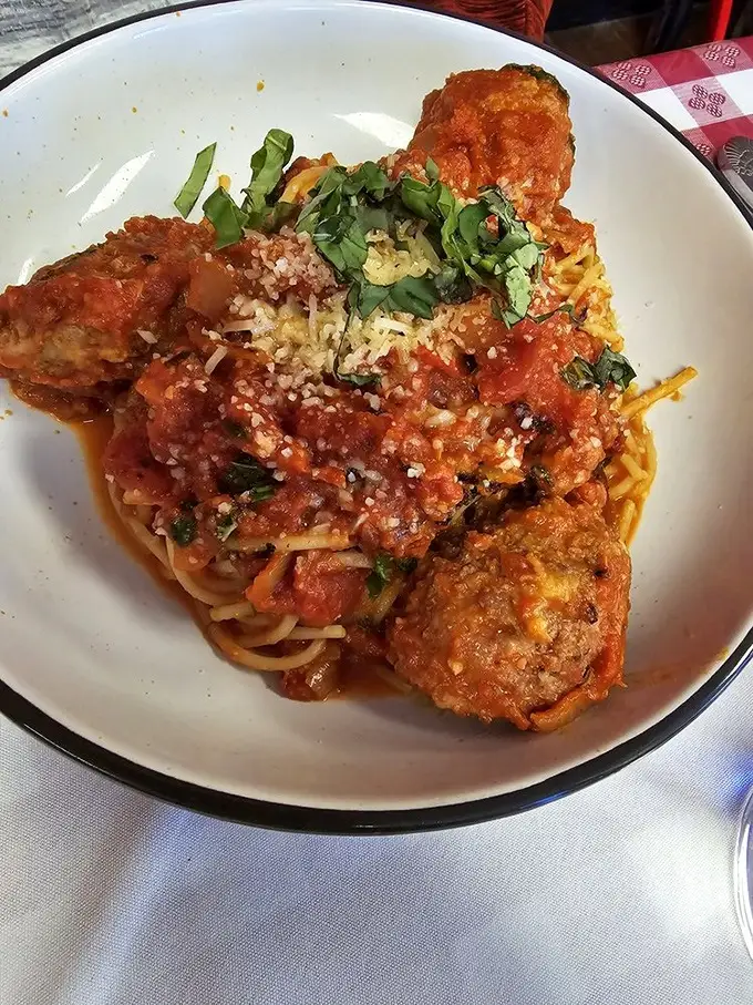 These meatballs aren't just sitting on the spaghetti—they're holding court. The generous dusting of Parmesan and fresh basil elevate this from meal to memory.