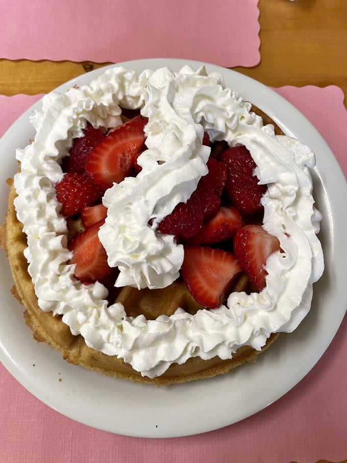 A mountain of whipped cream cradles fresh strawberries atop a golden waffle – proof that sometimes the best architecture isn't in buildings but on plates.