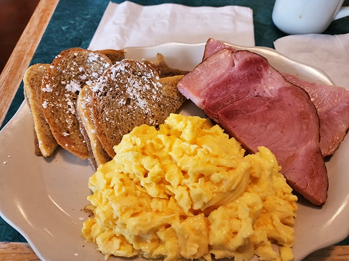 Classic breakfast perfection doesn't need fancy plating – just perfectly scrambled eggs, ham sliced thick enough to mean business, and French toast dusted with powdered sugar.
