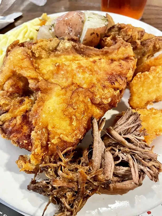 This isn't just fried chicken; it's a masterclass in crispiness. Golden-brown perfection sharing a plate with pulled pork that practically begs you to cancel your afternoon plans.