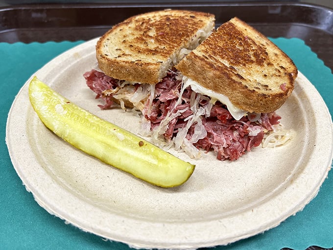 The Reuben in its natural habitat—accompanied by a pickle spear that's practically mandatory. This isn't just lunch; it's a religious experience on rye.
