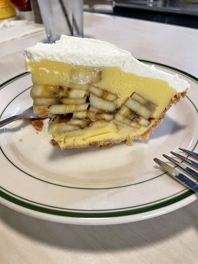 The cross-section reveals the architectural marvel that is The Apple Pan's banana cream pie – perfectly engineered layers that should be studied in culinary school.