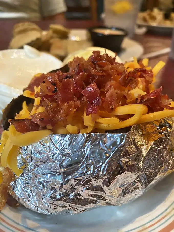 Cheese, bacon, and potato—the holy trinity of steakhouse sides—coming together in aluminum-wrapped perfection that would make a cardiologist wince.