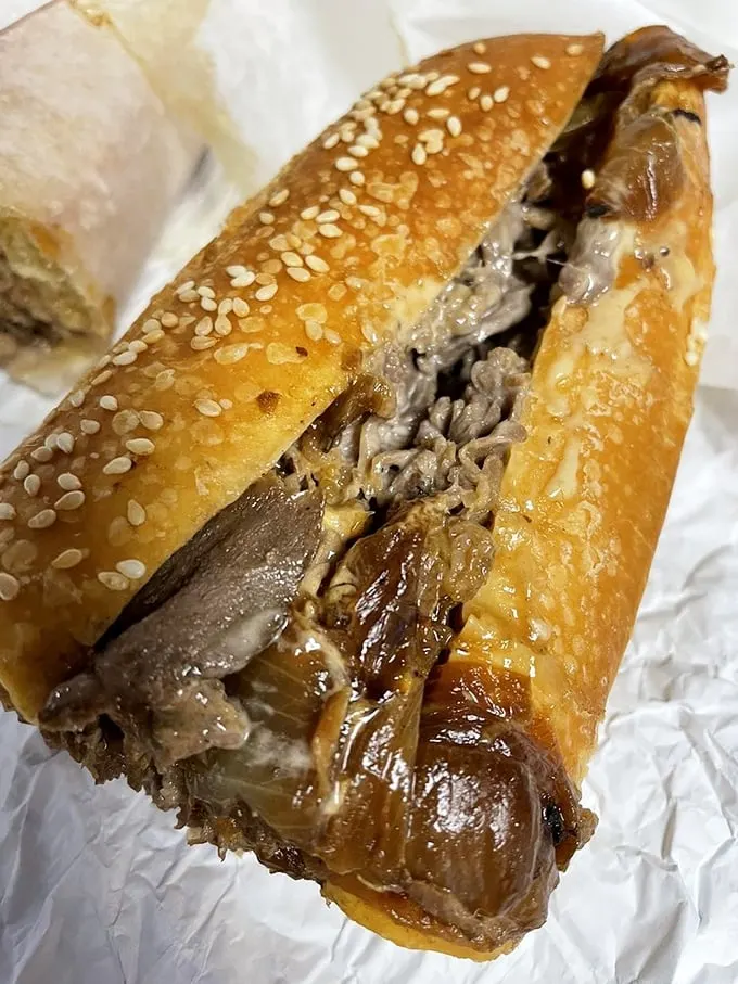 The sesame-seeded roll cradles thinly sliced steak and caramelized onions like they're precious cargo—which, let's be honest, they absolutely are.