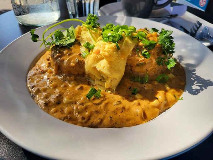 Gravy so good it deserves its own ZIP code, cradling what appears to be biscuits beneath a blanket of savory goodness and fresh herbs. 