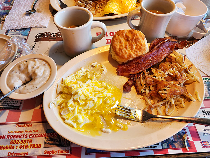 Breakfast perfection on a plate—fluffy scrambled eggs, crispy bacon, golden hashbrowns, and a biscuit that would make your grandmother both jealous and proud.