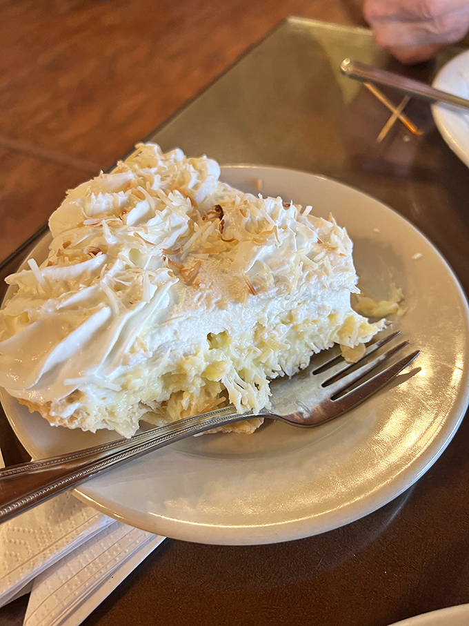 The coconut cream pie arrives like a snow-capped mountain of sweetness, with shredded coconut creating a blizzard of flavor in every bite.