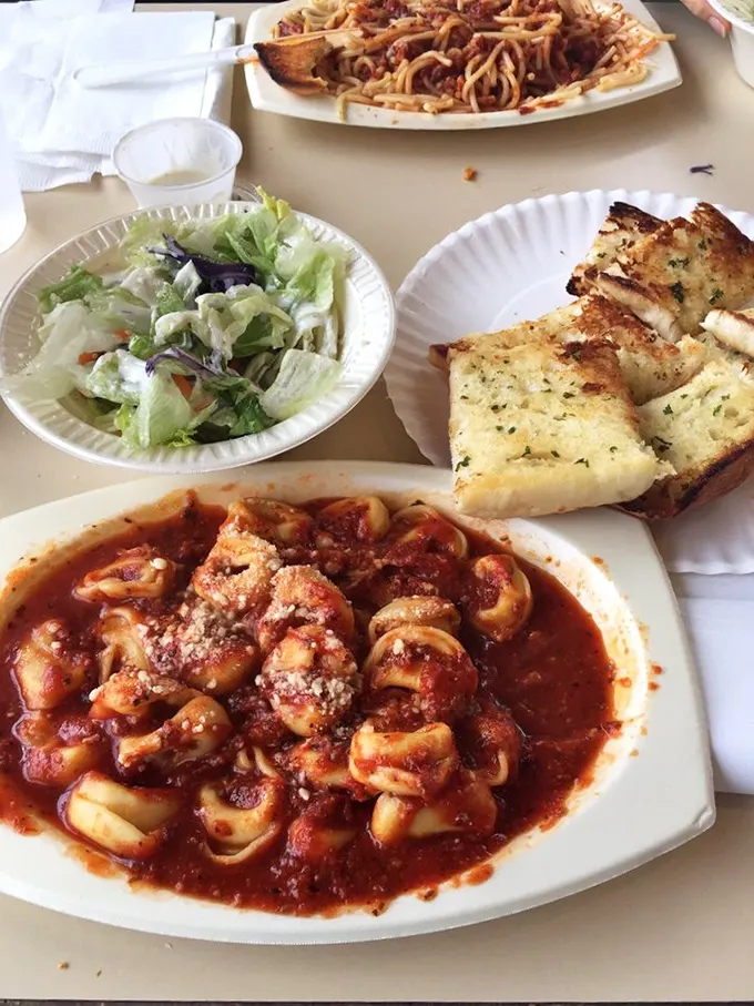 Tortellini swimming in that signature red sauce, garden-fresh salad, and golden garlic bread—the kind of meal that ruins diets but creates memories.