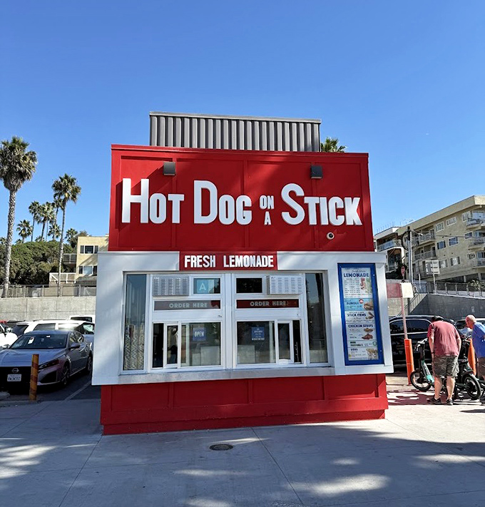 Hot Dog on a Stick's bold red stand against the California sky – a beacon of fried perfection that's outlasted countless food trends.