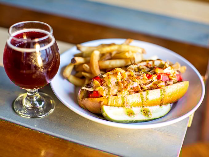 When a hot dog evolves from ballpark necessity to culinary statement – complete with gourmet toppings and that ruby beer companion.