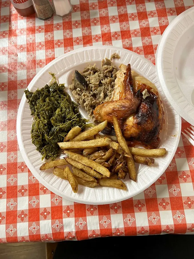 The classic trifecta: smoky pulled pork, garden-fresh collards, and golden-brown chicken—a plate that tells North Carolina's culinary story better than any book.